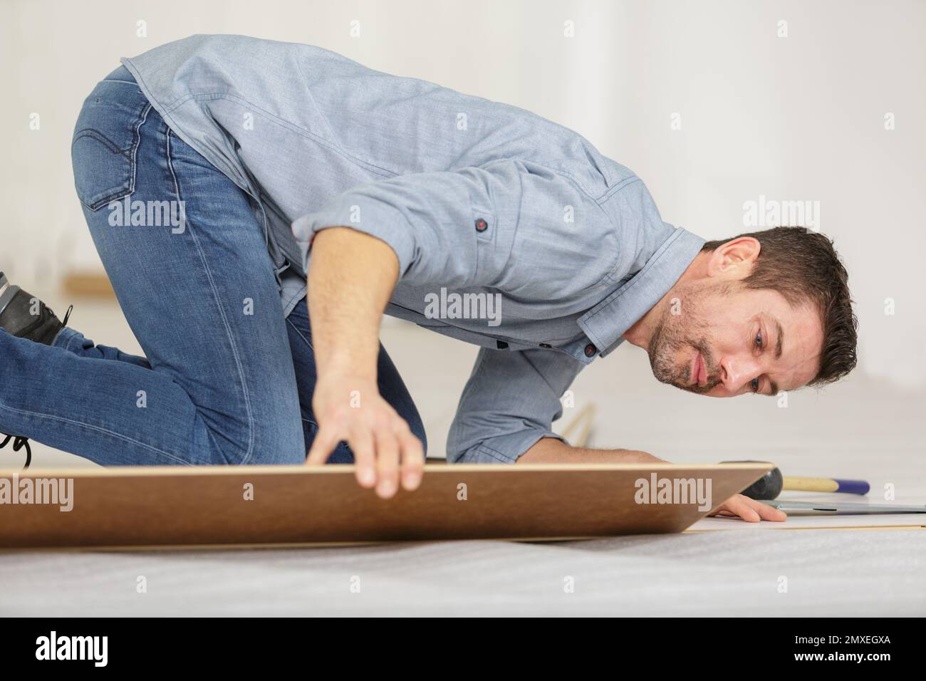 laminate flooring man in sneakers repair Stock Photo - Alamy