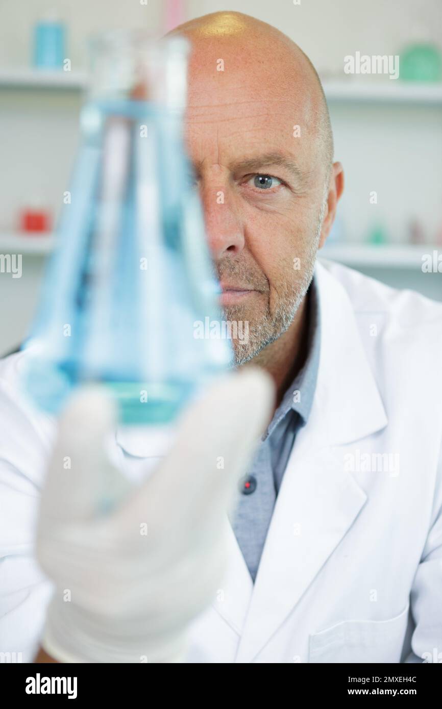 male scientist holding erlenmeyer flask partially covering his face ...