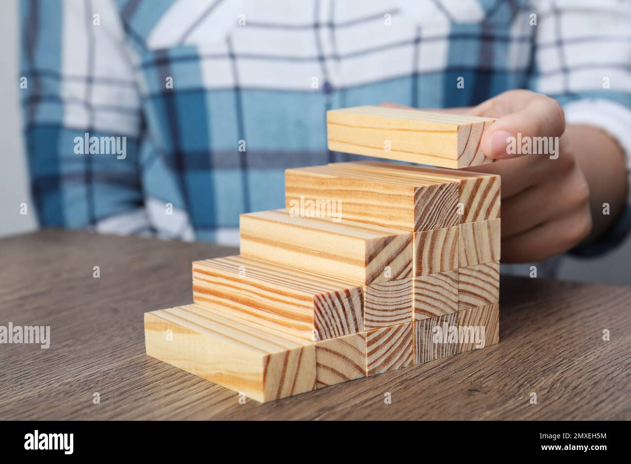 Woman building steps with wooden blocks at table, closeup. Career ...
