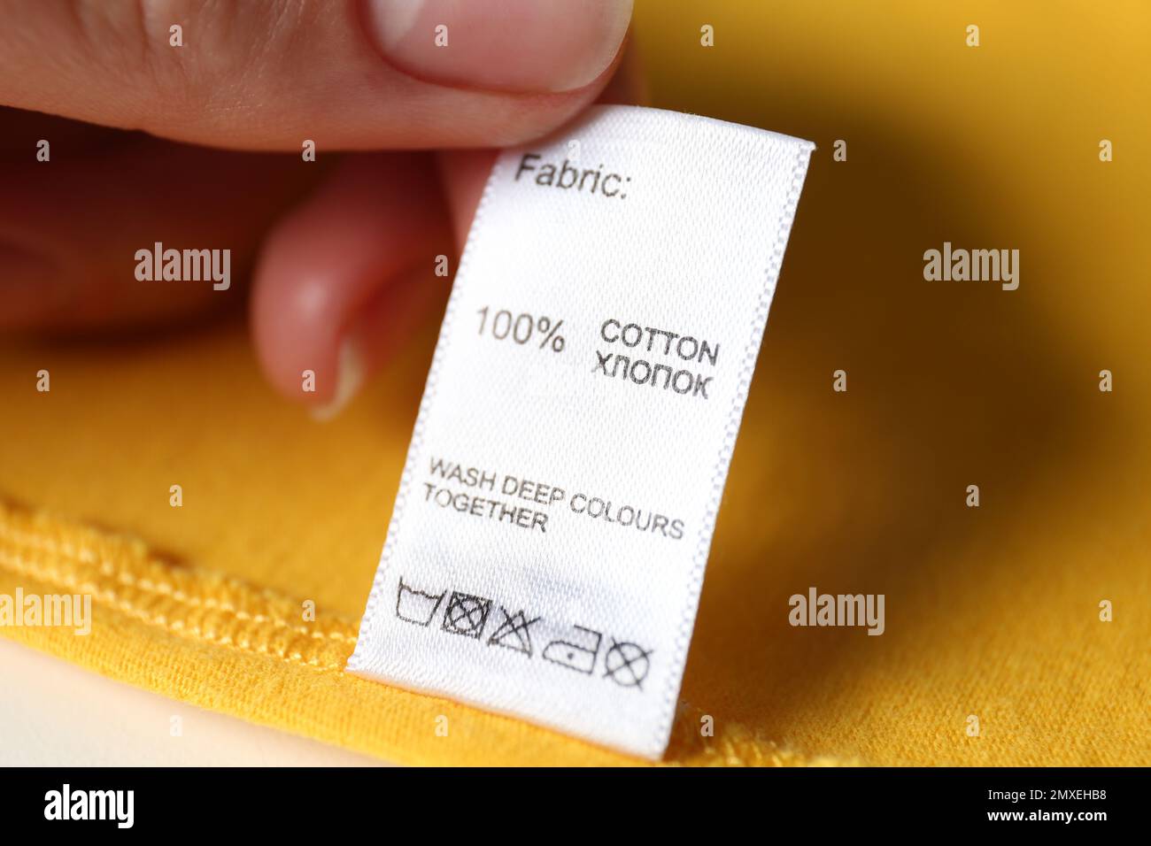 Woman reading clothing label with care symbols and material content on ...