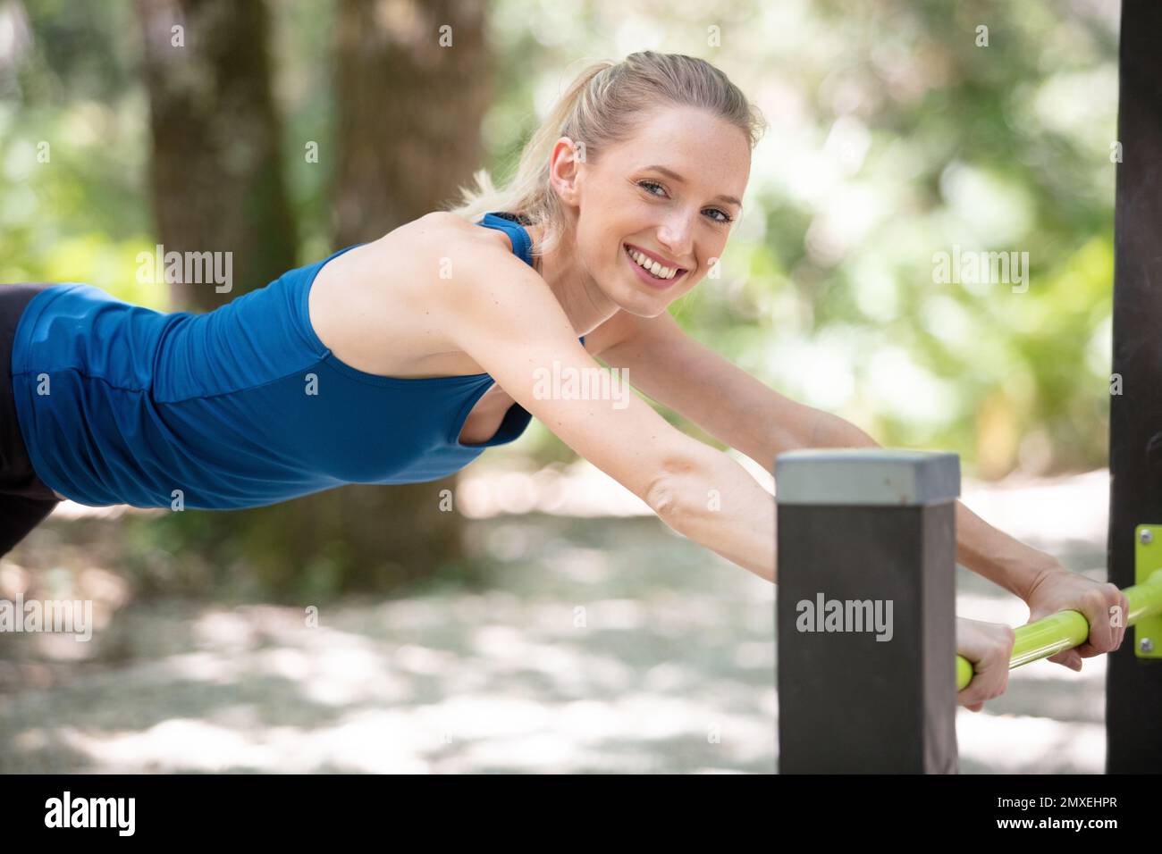 beautiful young woman exercising on outdoor parallel bars doing push ...