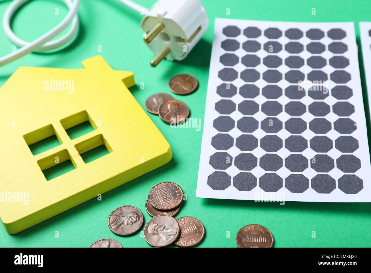 Solar panels, house model and coins on green background Stock Photo - Alamy