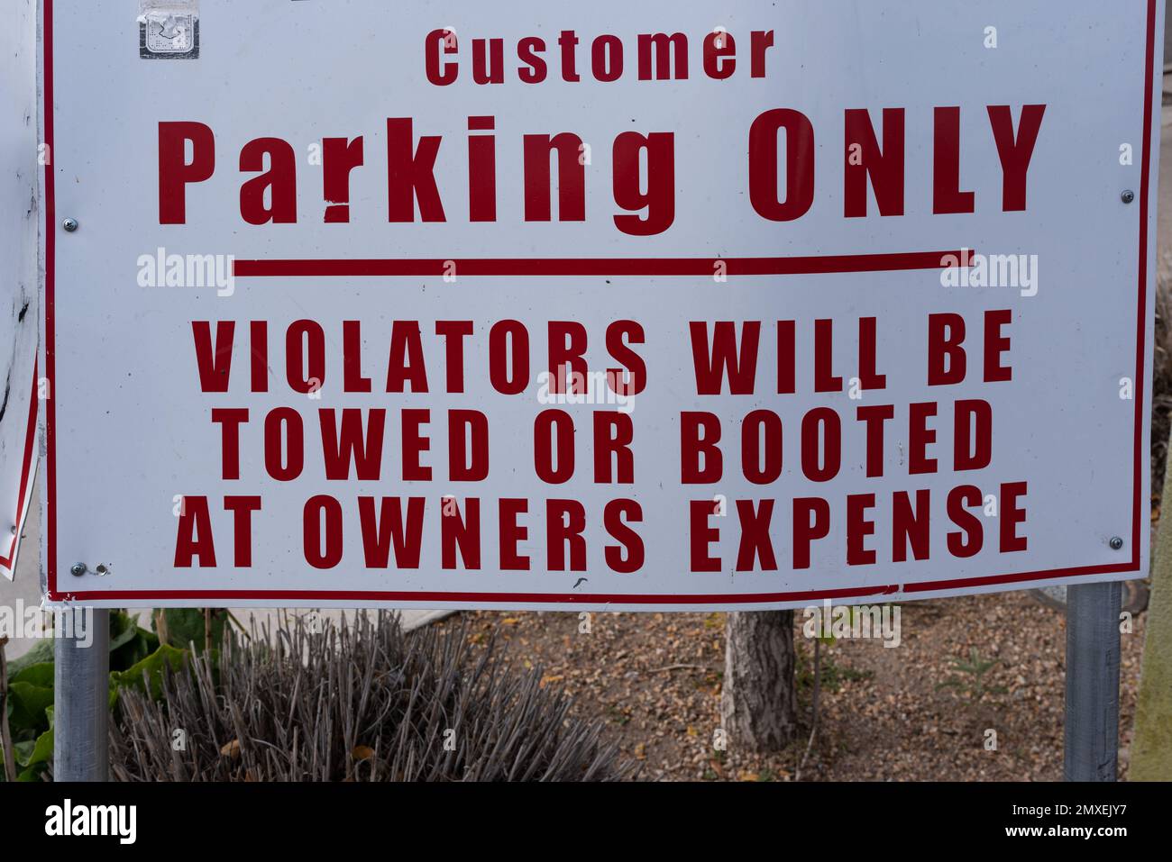 A white sign with red letters reads, Customer Parking Only, Violators ...