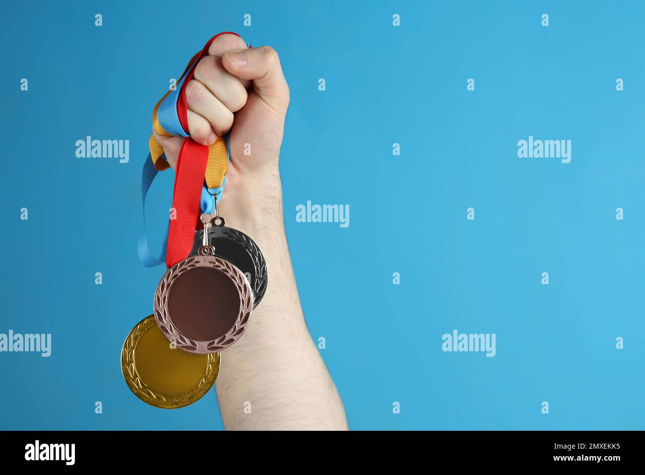 Man holding medals on blue background, closeup. Space for design Stock ...