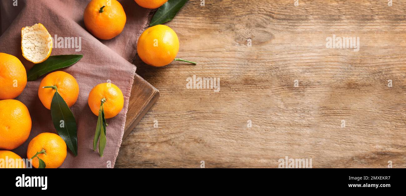 Fresh ripe tangerines with leaves and space for text on wooden table ...