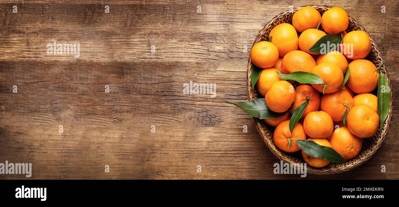 Fresh ripe tangerines with leaves and space for text on wooden table ...