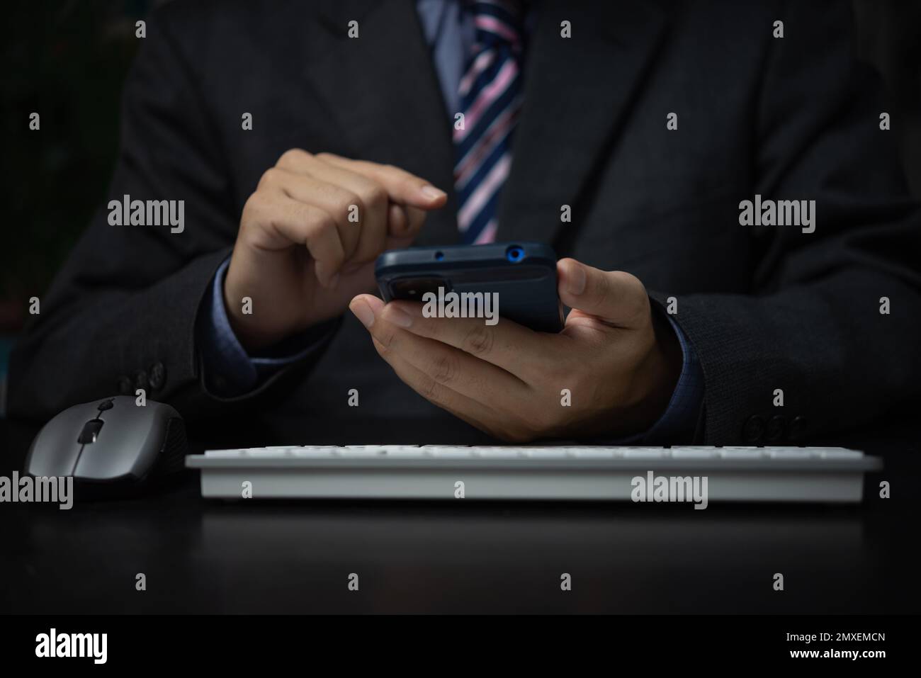 Business man holding mobile smartphone and keyboard computer on desk ...