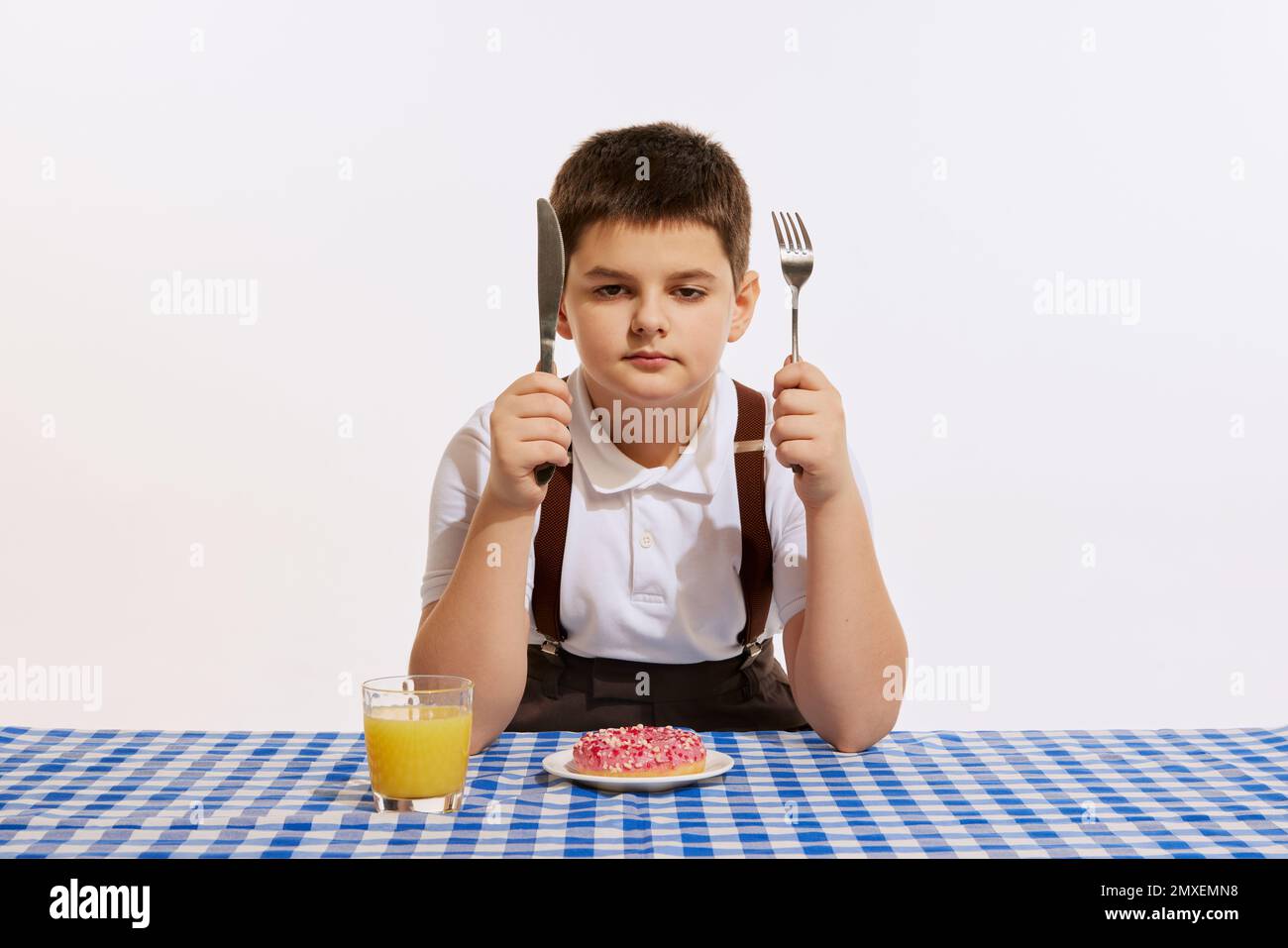 Cute little boy sitting at table covered plaid table cloth and having ...