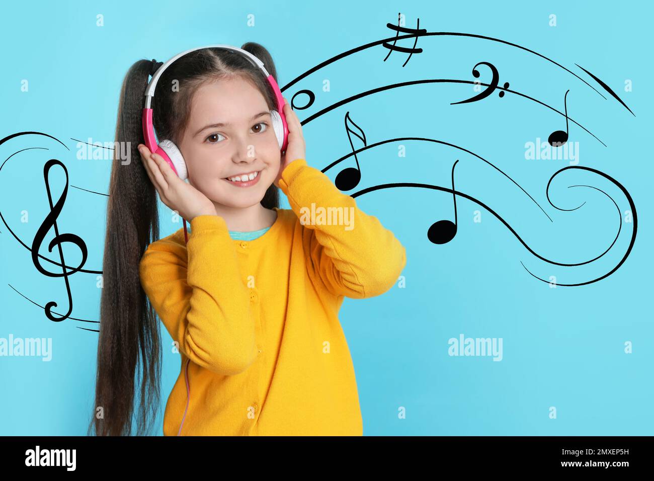 Cute girl listening to music through headphones on light blue ...