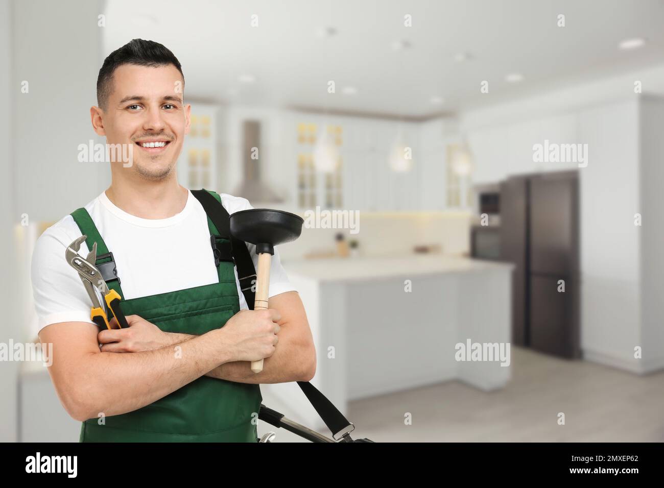 Plumber with adjustable wrench and force cup in kitchen, space for text ...