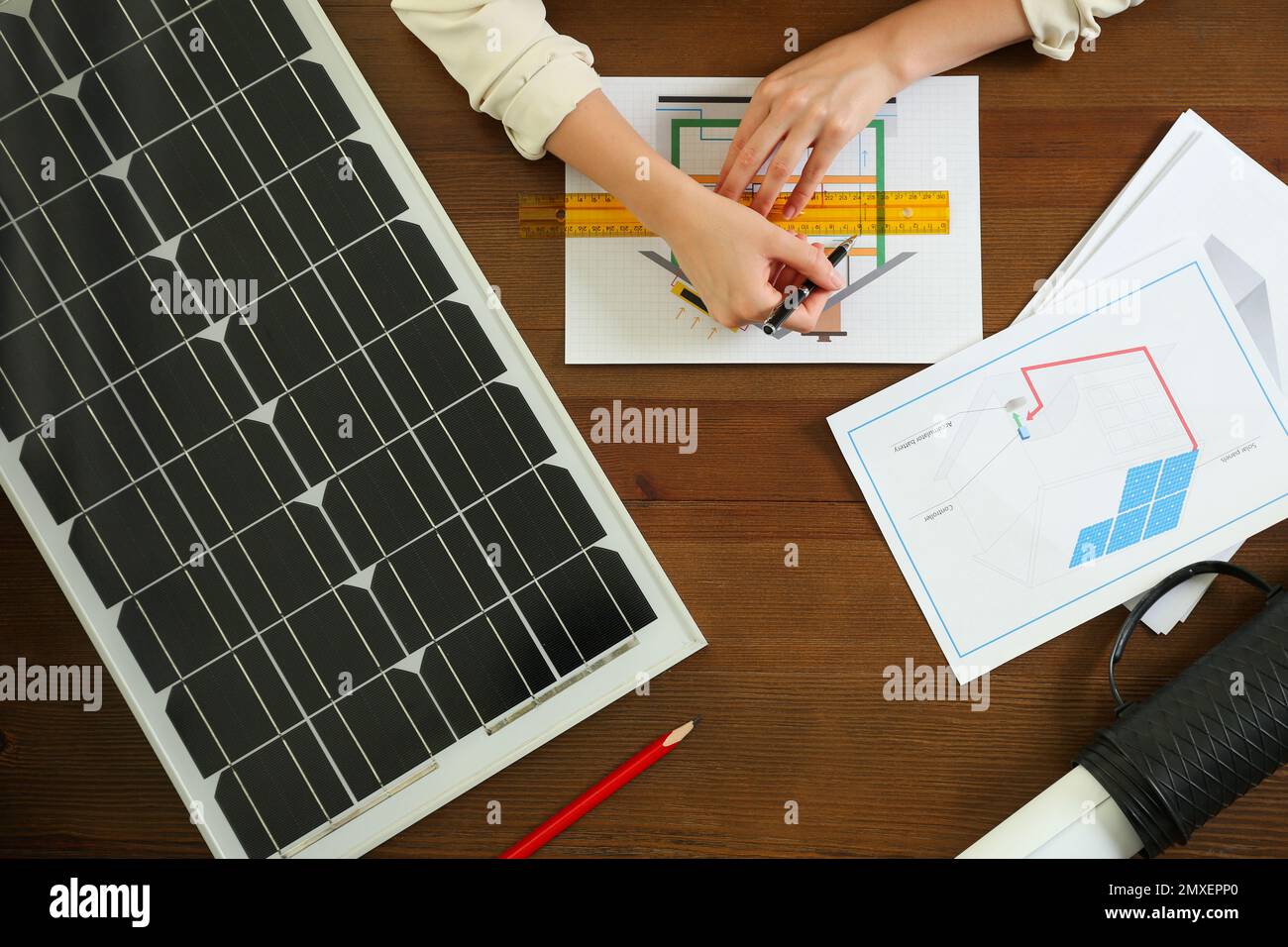 Architect working on house project with solar panels at wooden table ...