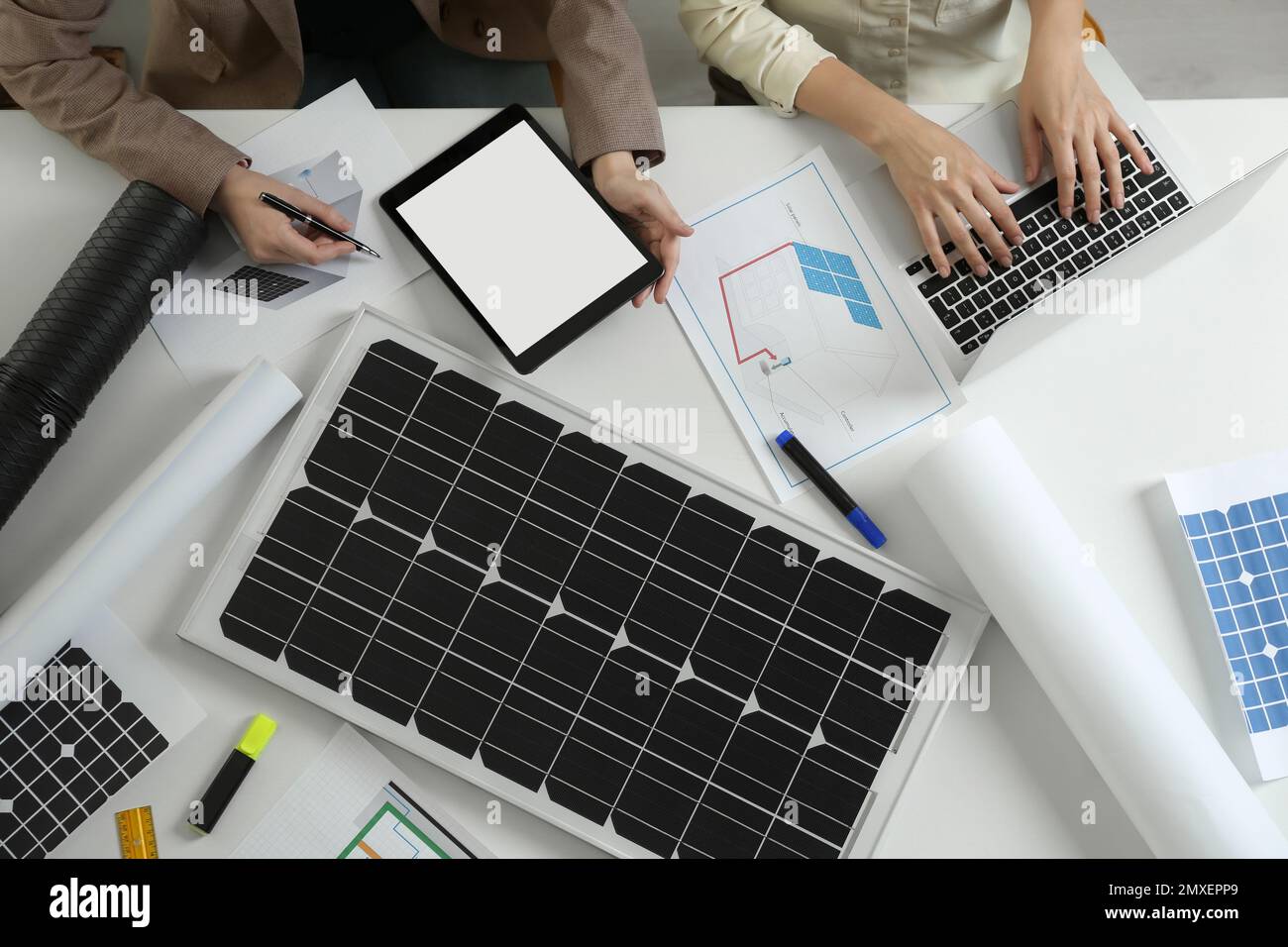 Architects working on house project with solar panels at white table ...