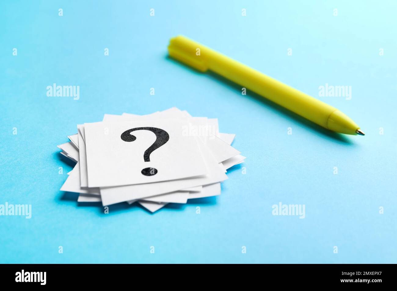 Heap of paper notes with question marks and pen on light blue ...