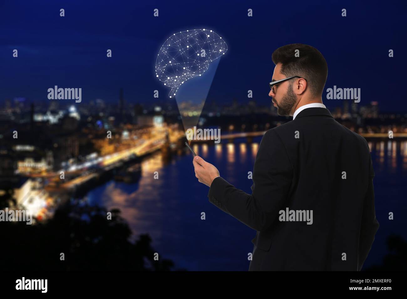 Young man using smartphone with virtual image of brain and night ...