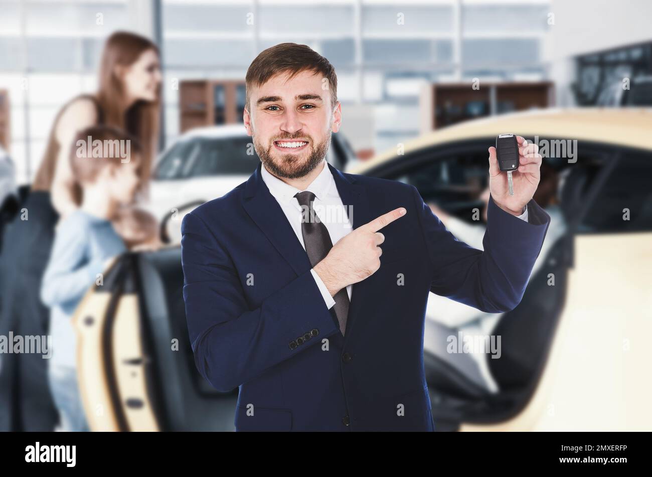 Happy salesman with key in car salon Stock Photo - Alamy