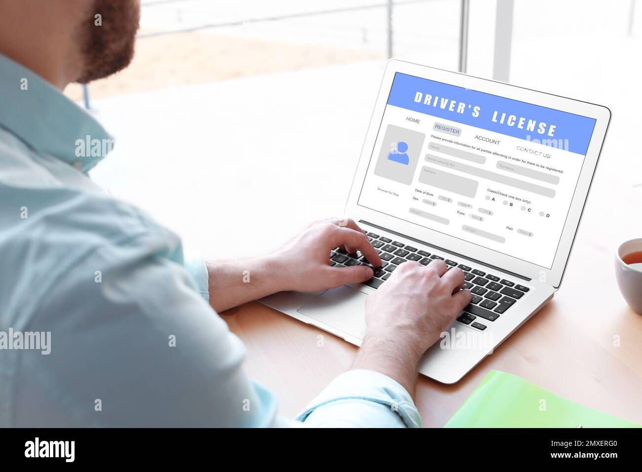 Man filling in driver's license form online on website using laptop ...