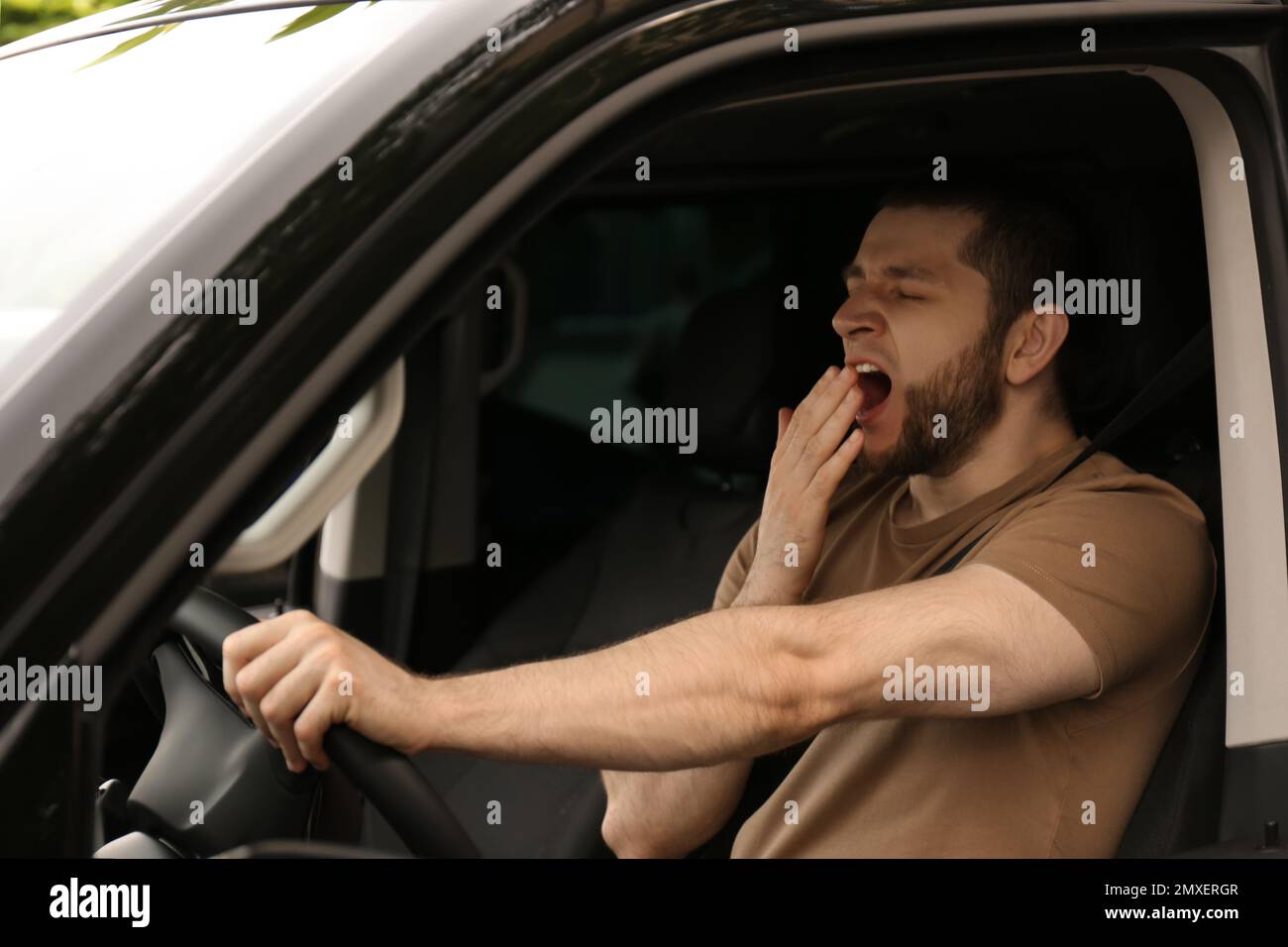 Tired man yawning while driving his modern car Stock Photo - Alamy