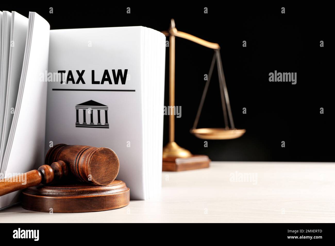 Tax law book, judge's gavel and scales on white table against black ...