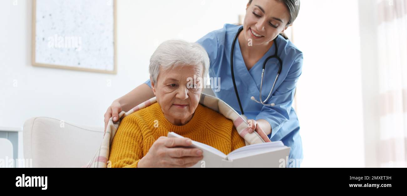 Care worker covering elderly woman with plaid in geriatric hospice ...