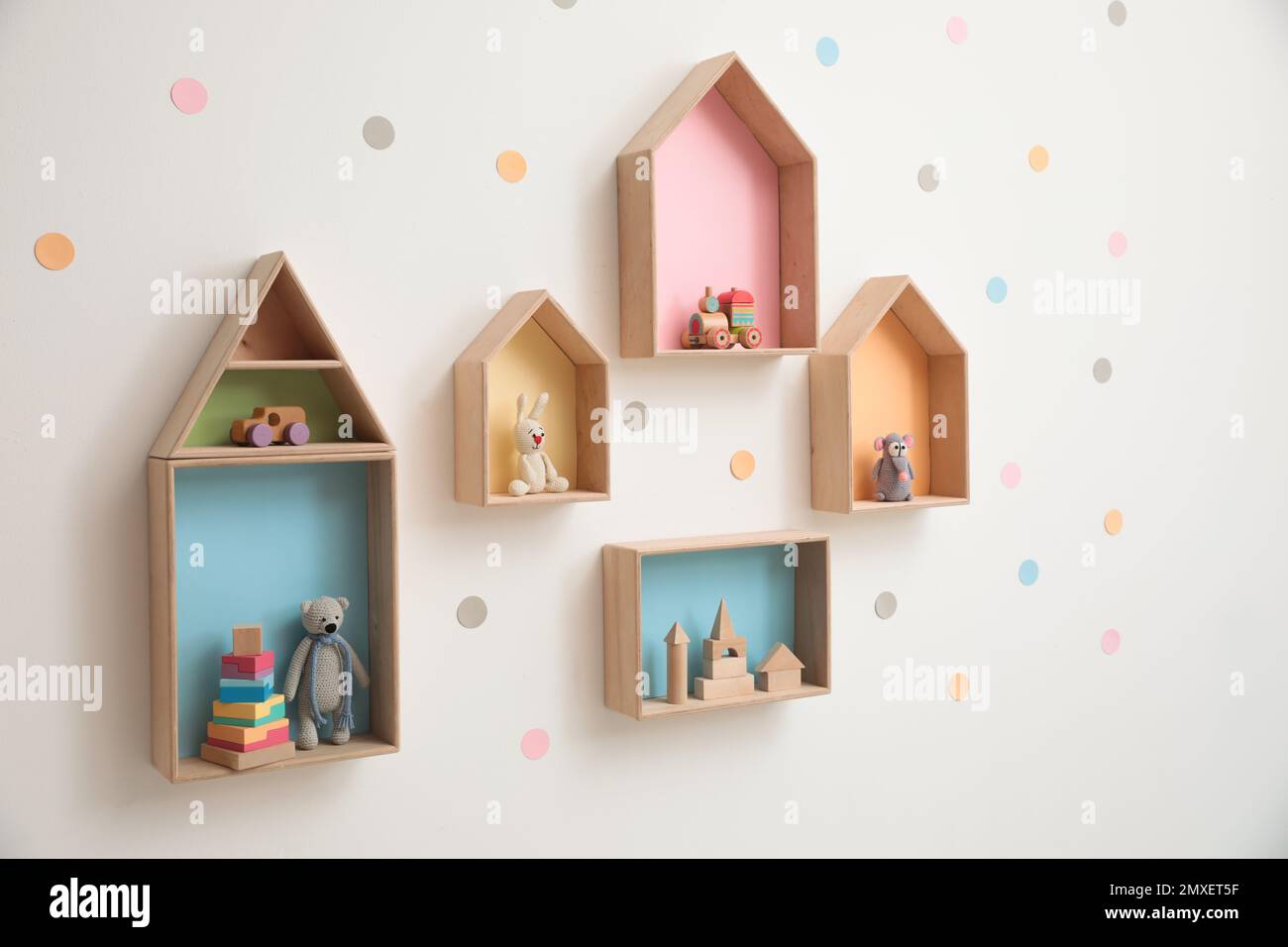 Stylish house shaped shelves with toys on white wall. Baby room ...