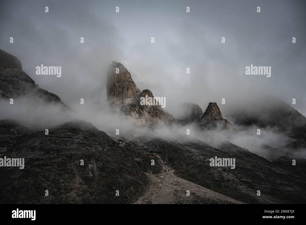 Dark atmospheric surreal landscape with dark rocky mountain top in low ...
