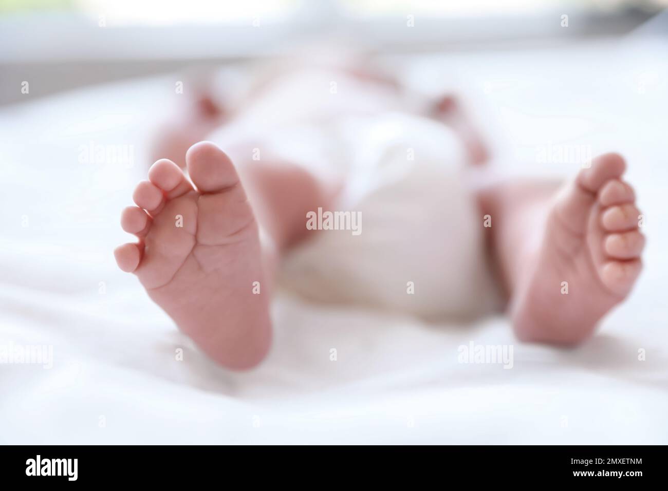 Newborn baby lying on bed, closeup of legs Stock Photo - Alamy