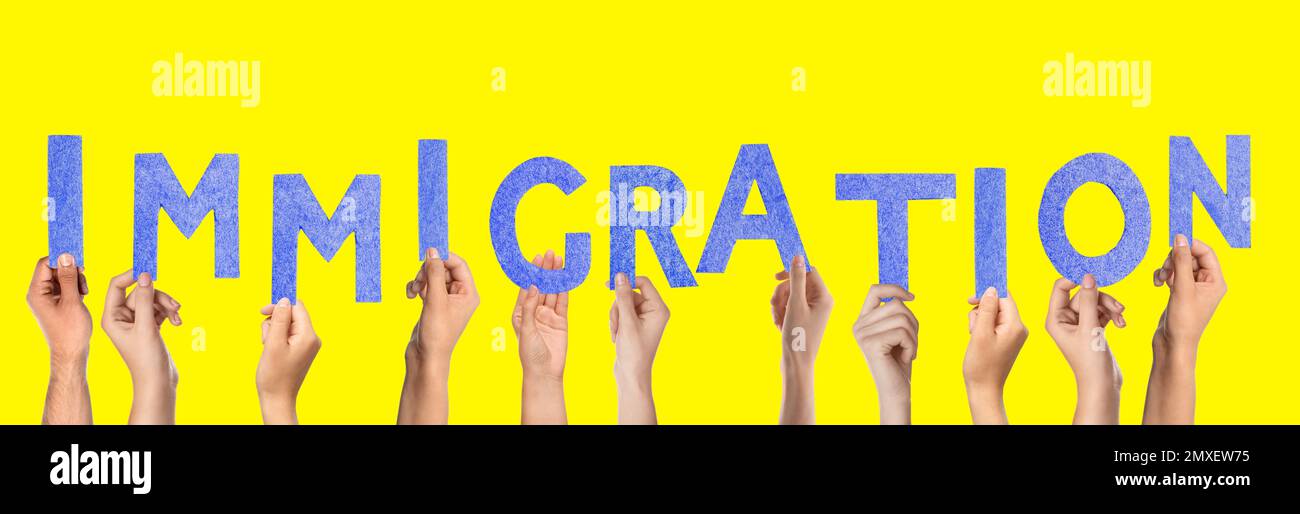 People holding word IMMIGRATION made of cardboard letters on yellow ...