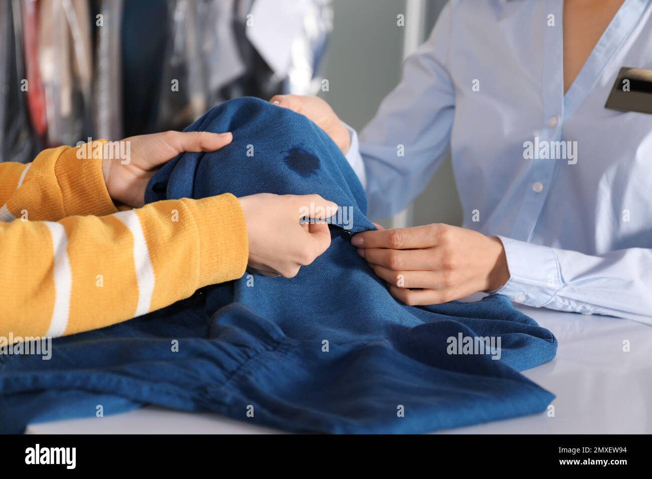 Female worker receiving clothes from client at dry-cleaner's, closeup ...