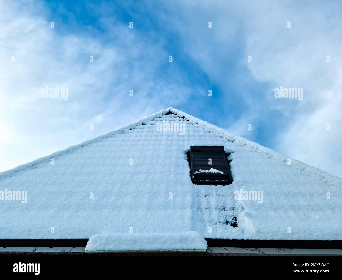 Open roof window in velux style with black roof tiles covered in snow ...