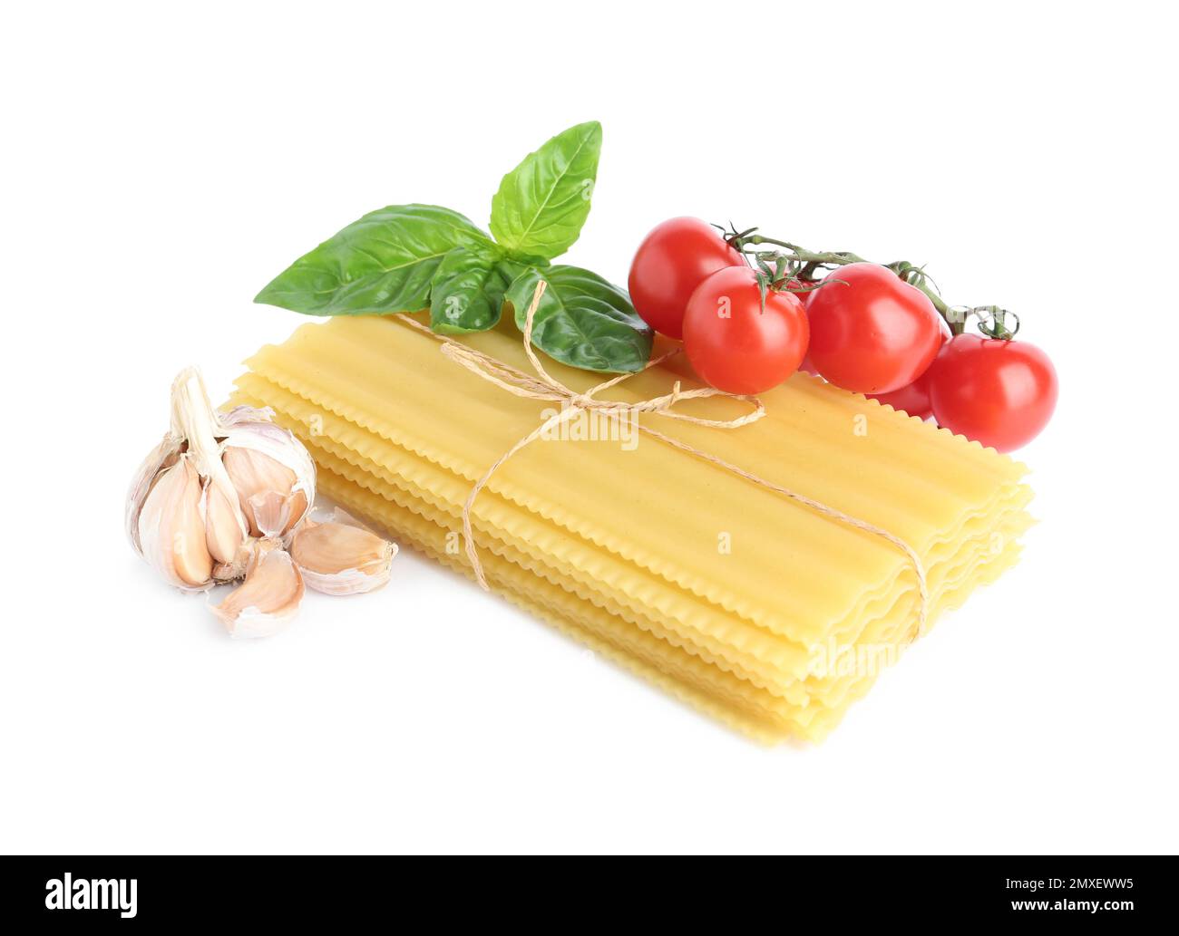 Uncooked lasagna sheets with cherry tomatoes, garlic and basil isolated ...