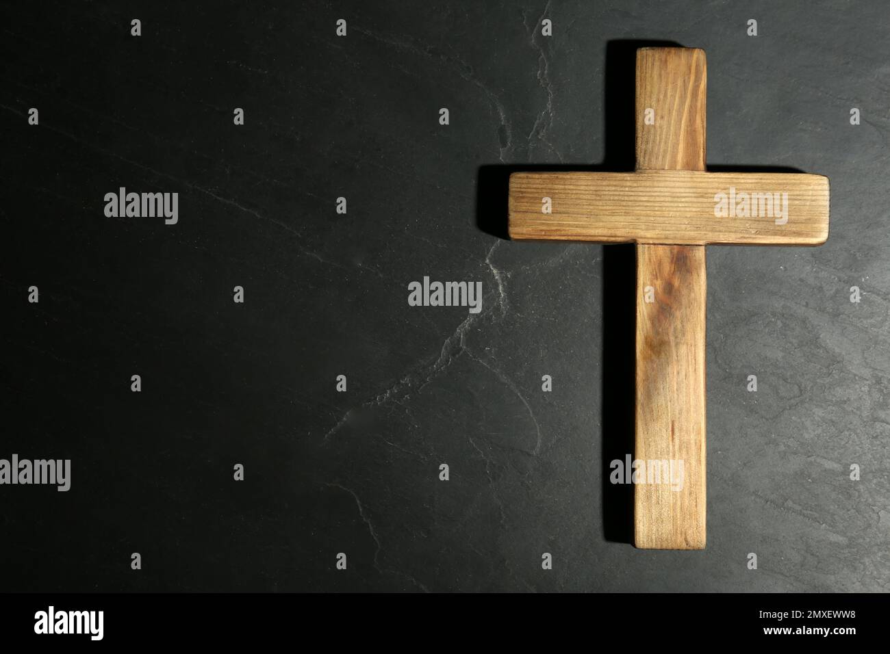 Wooden Christian cross on black slate table, top view with space for ...