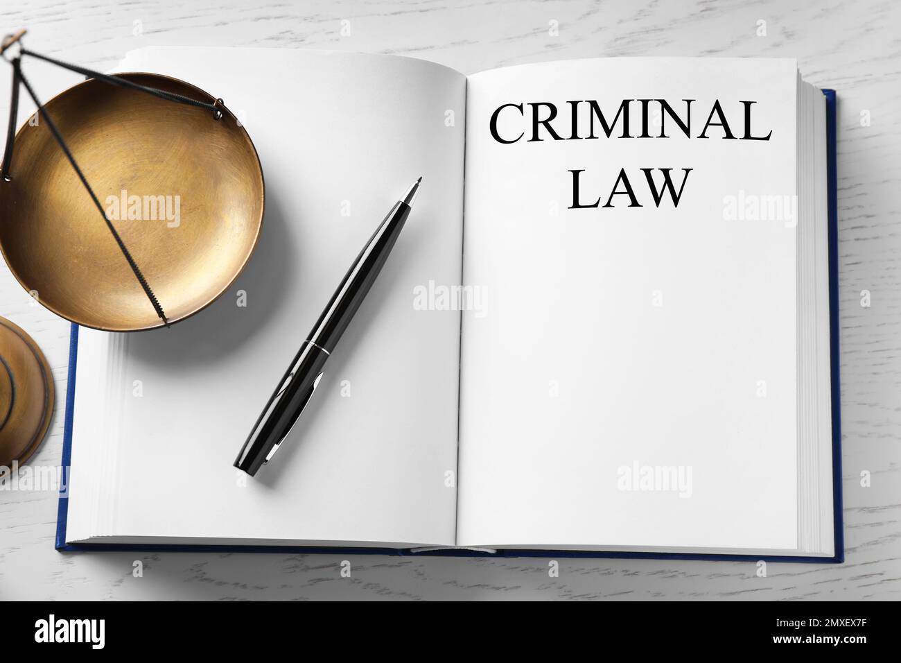 Scales of justice and book on white wooden table, top view. Criminal ...