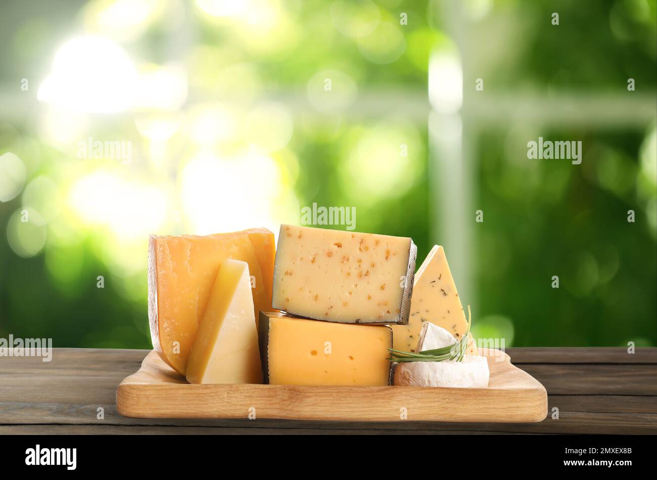 Different types of delicious cheeses on wooden table outdoors. Dairy ...