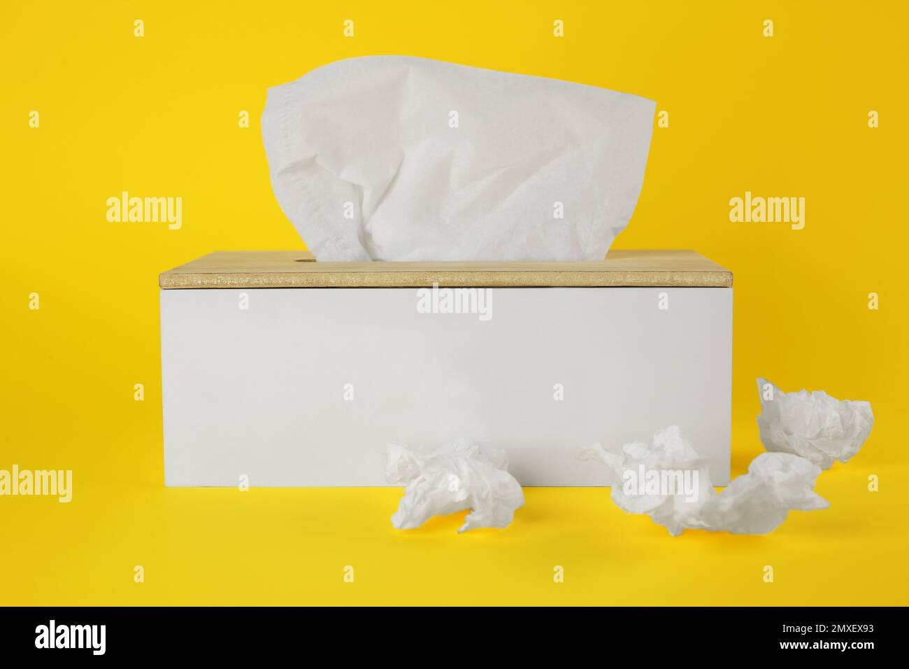 Used paper tissues and holder on yellow background Stock Photo - Alamy