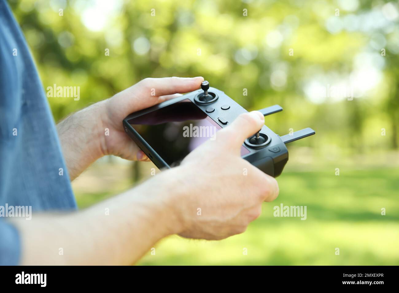 Man holding new modern drone controller outdoors, closeup of hands ...