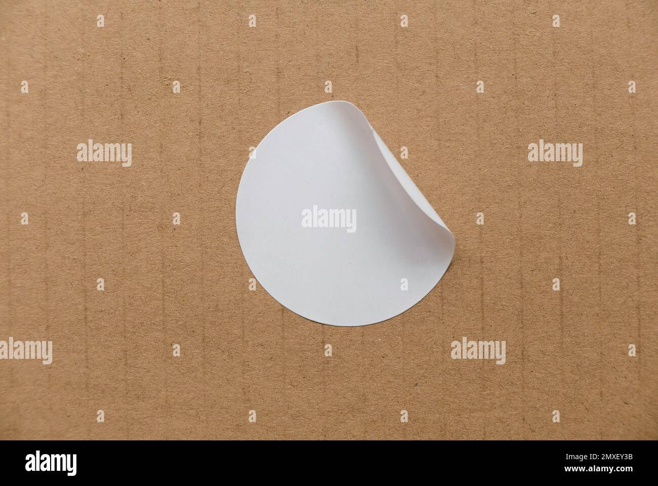 Blank white round stickers with folded corner on cardboard background ...