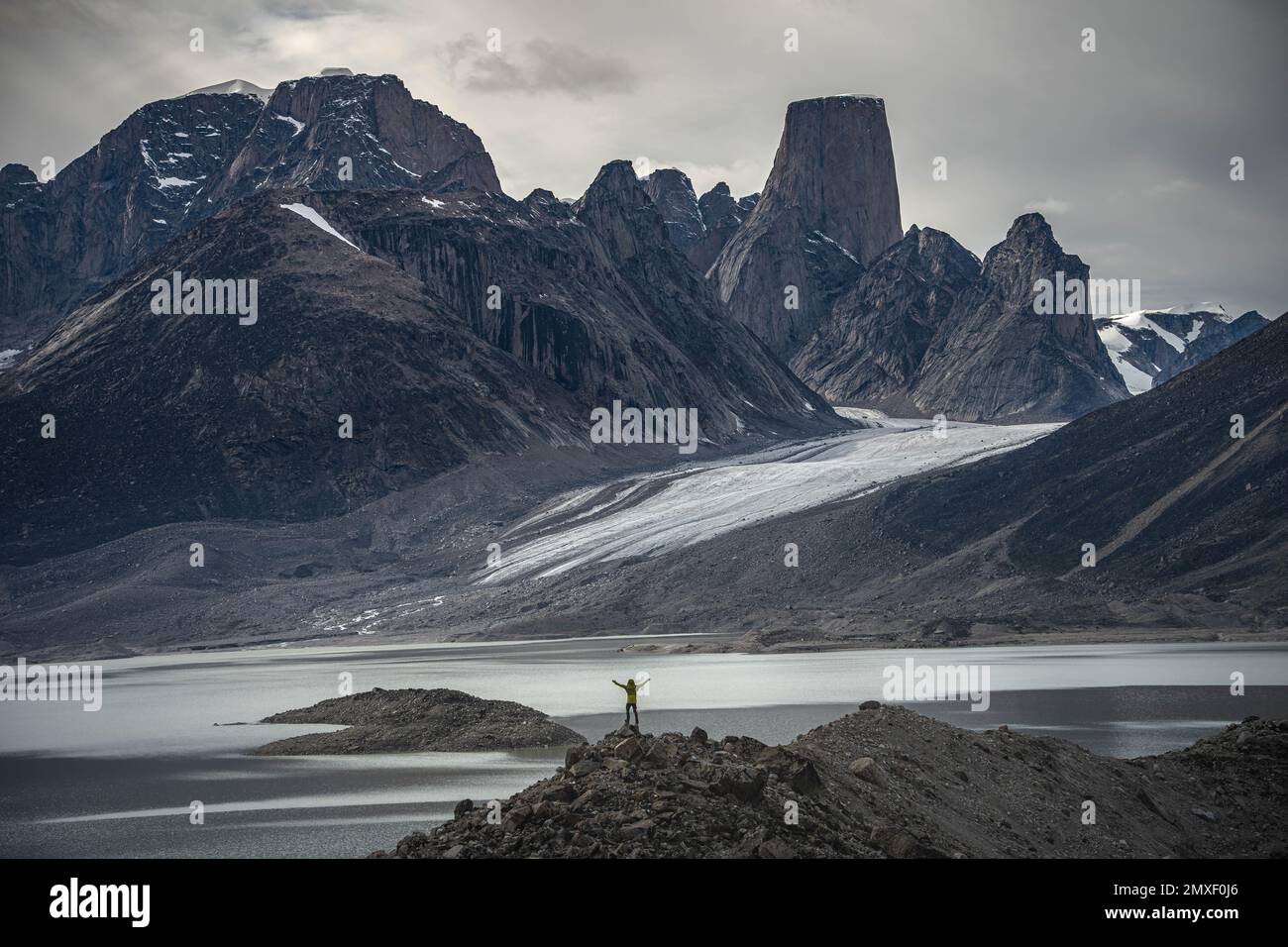 Hiker standing on the peack with Mount Asgard, Baffin Island on ...