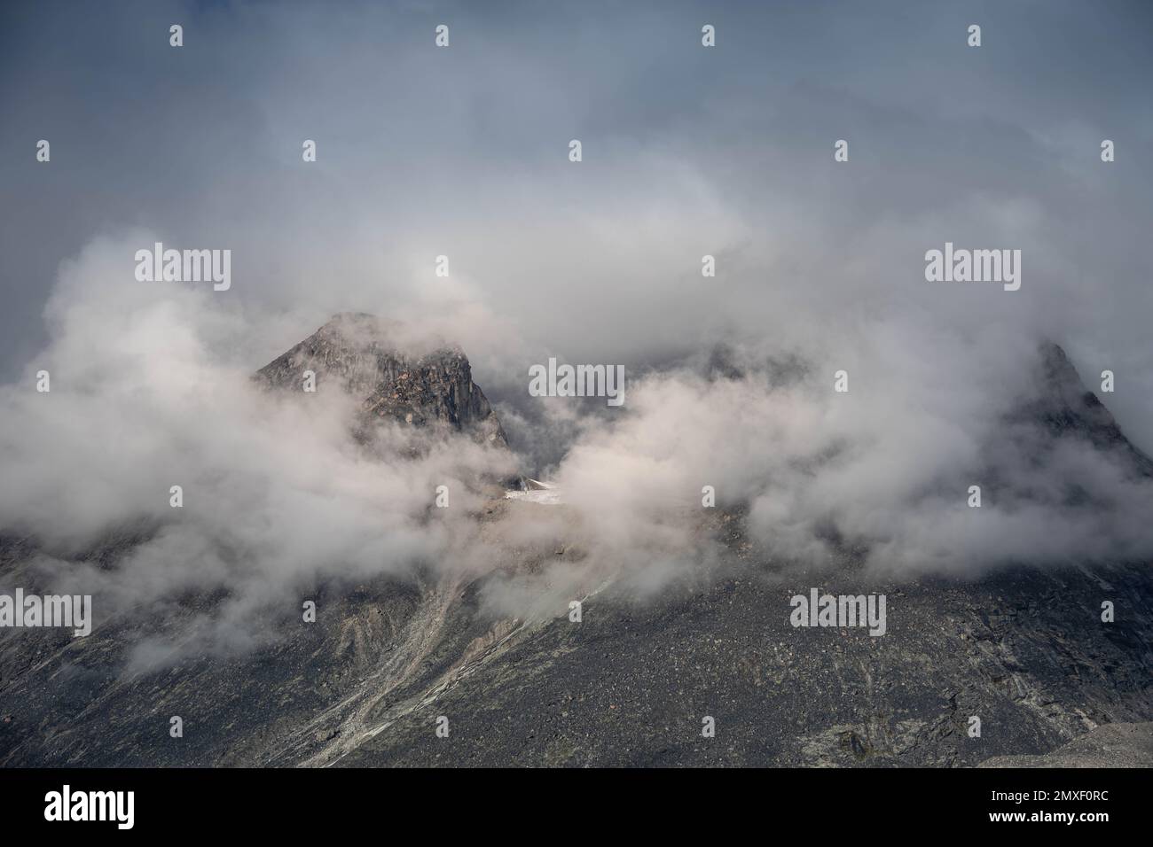 Dark atmospheric surreal landscape with dark rocky mountain top in low ...