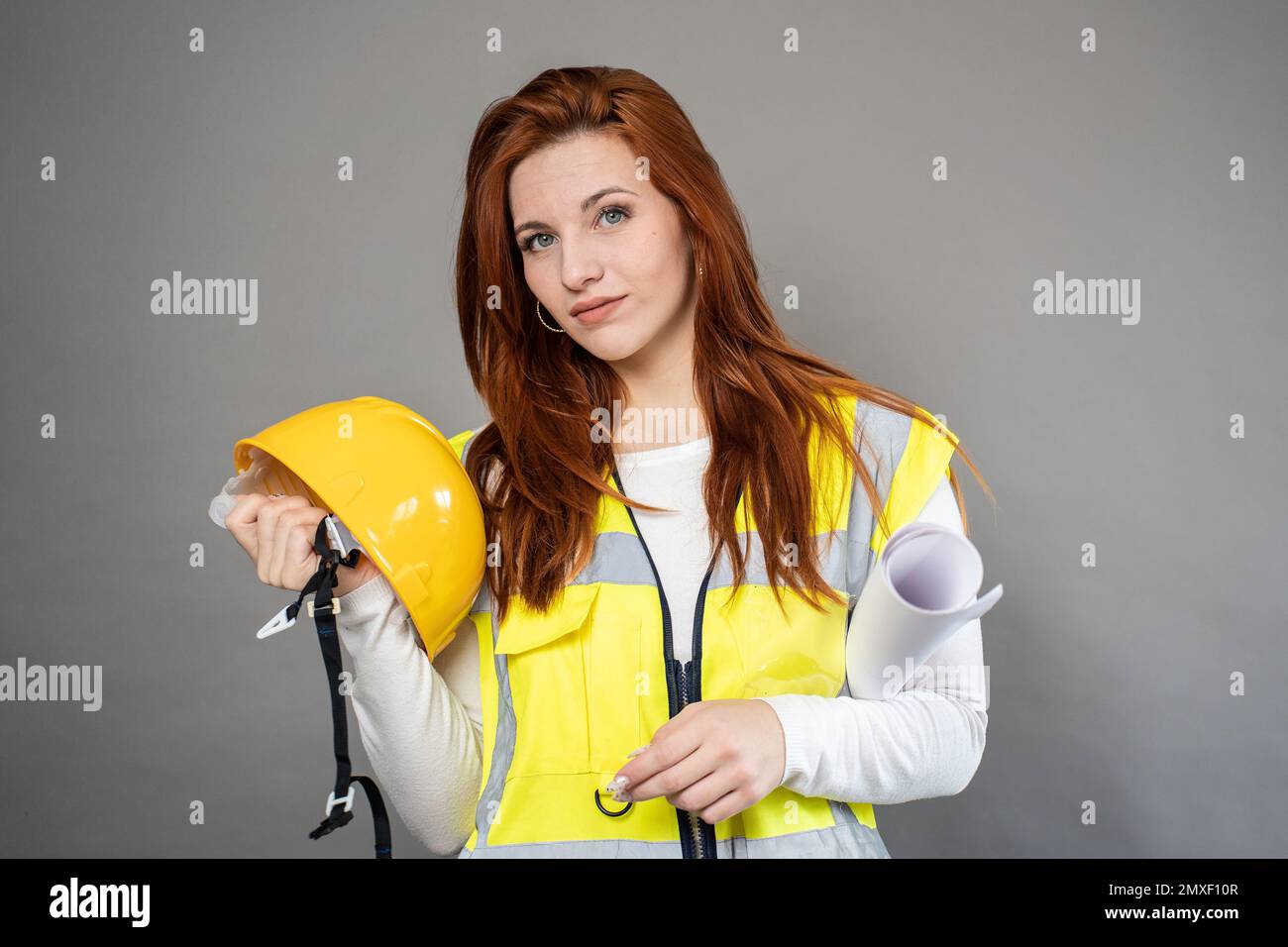 Young female redhead worker of construction site wearing a safety vest ...