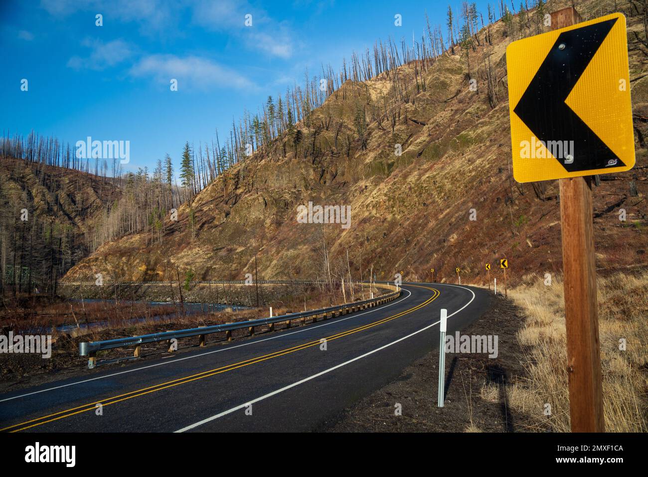 A view of a road with a sharp curve ahead road sign Stock Photo - Alamy