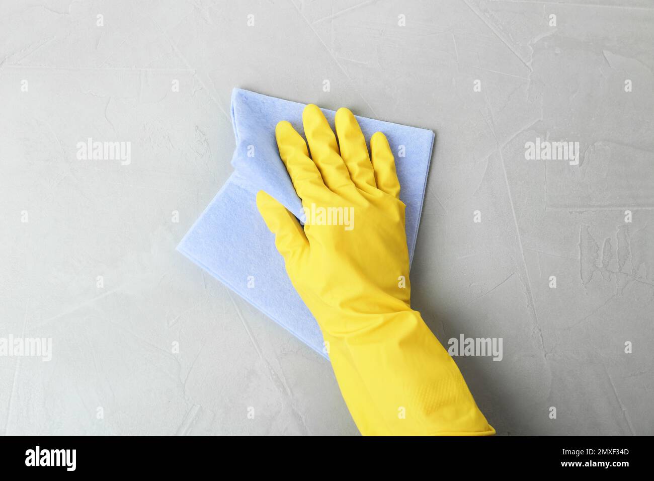 Person in gloves wiping grey table with rag, top view Stock Photo - Alamy