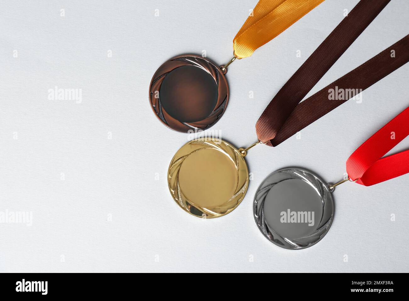 Gold, silver and bronze medals on white background, flat lay. Space for ...