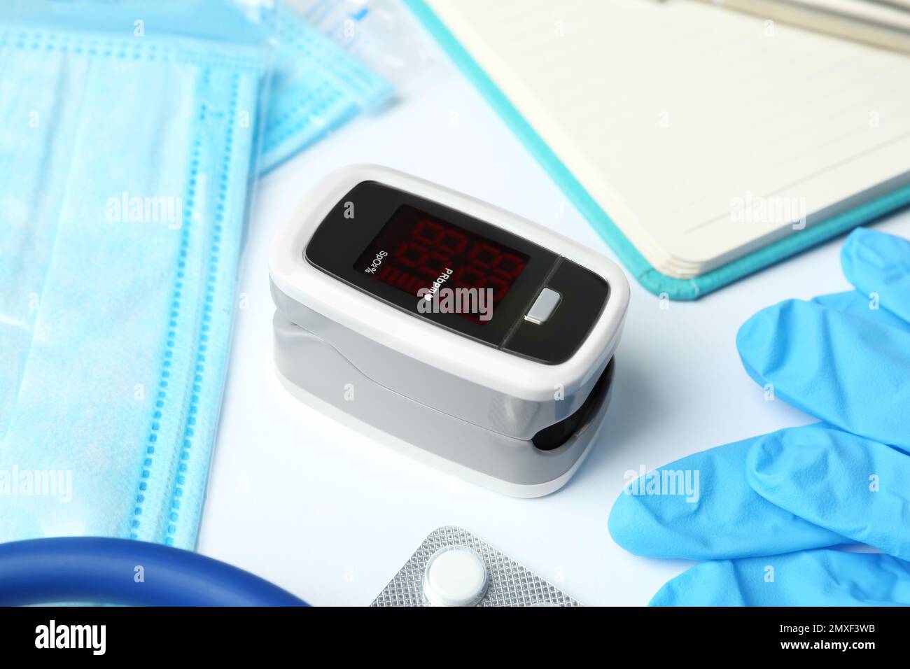 Modern fingertip pulse oximeter and medical items on white background ...