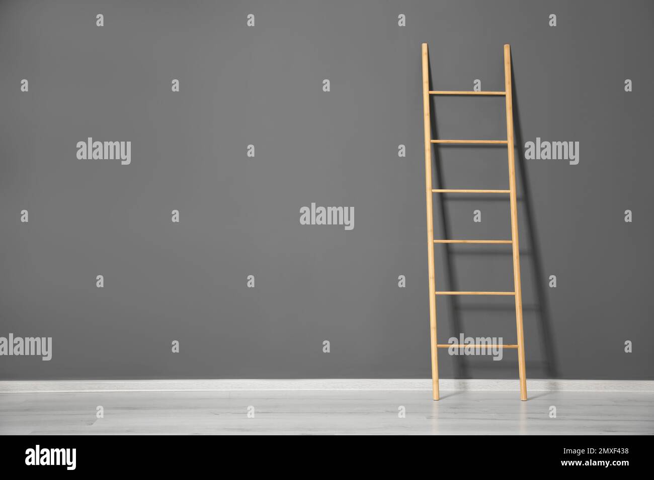 Modern wooden ladder near grey wall. Space for text Stock Photo - Alamy
