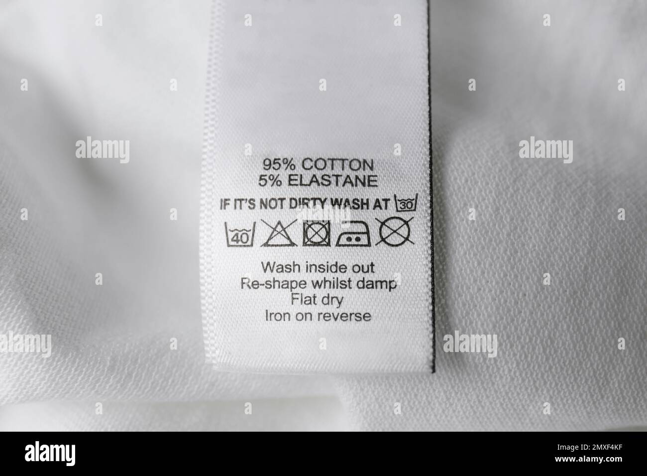 Clothing label with care symbols and material content on white shirt ...