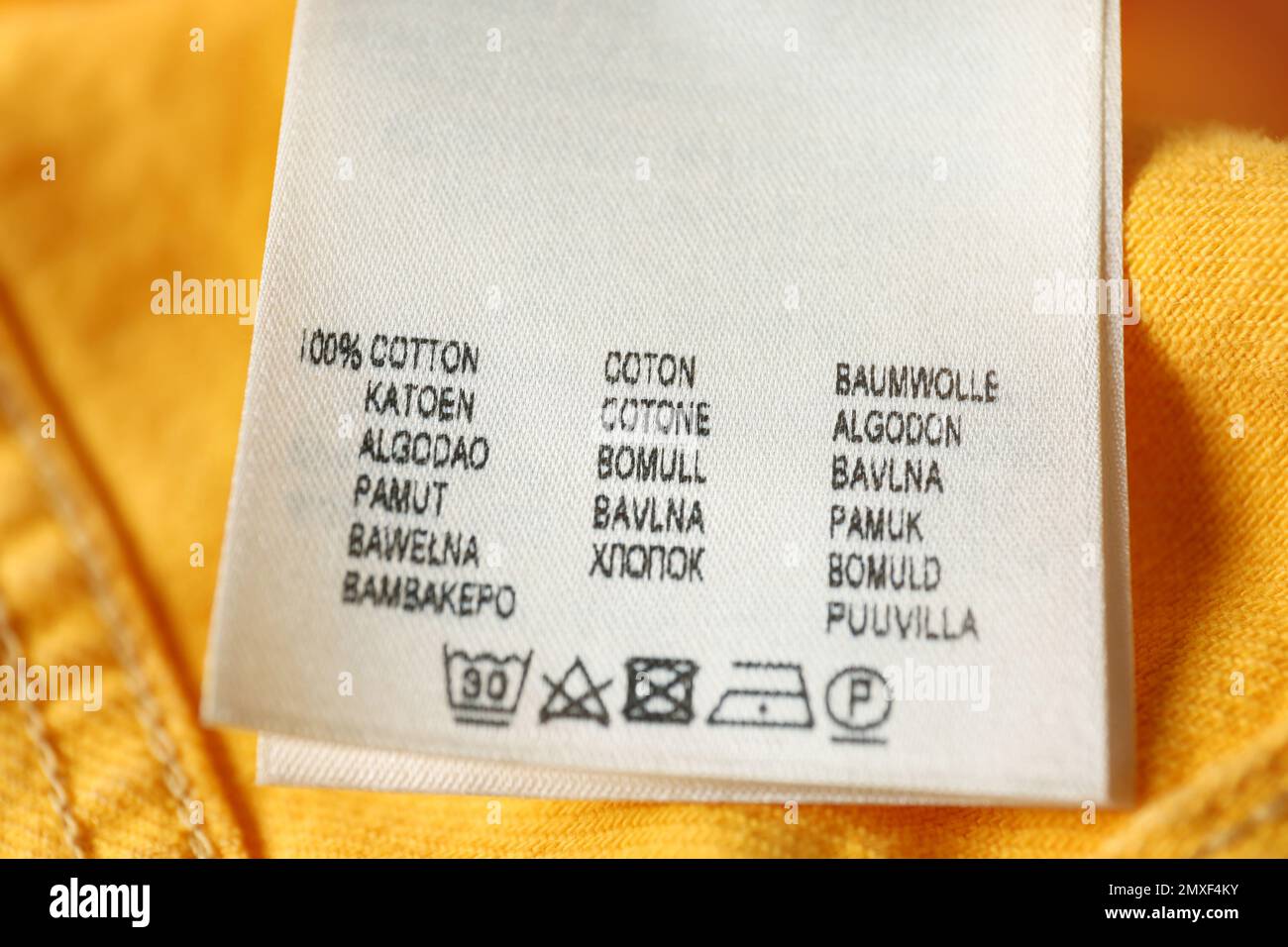 Clothing label with care symbols and material content on yellow jeans ...