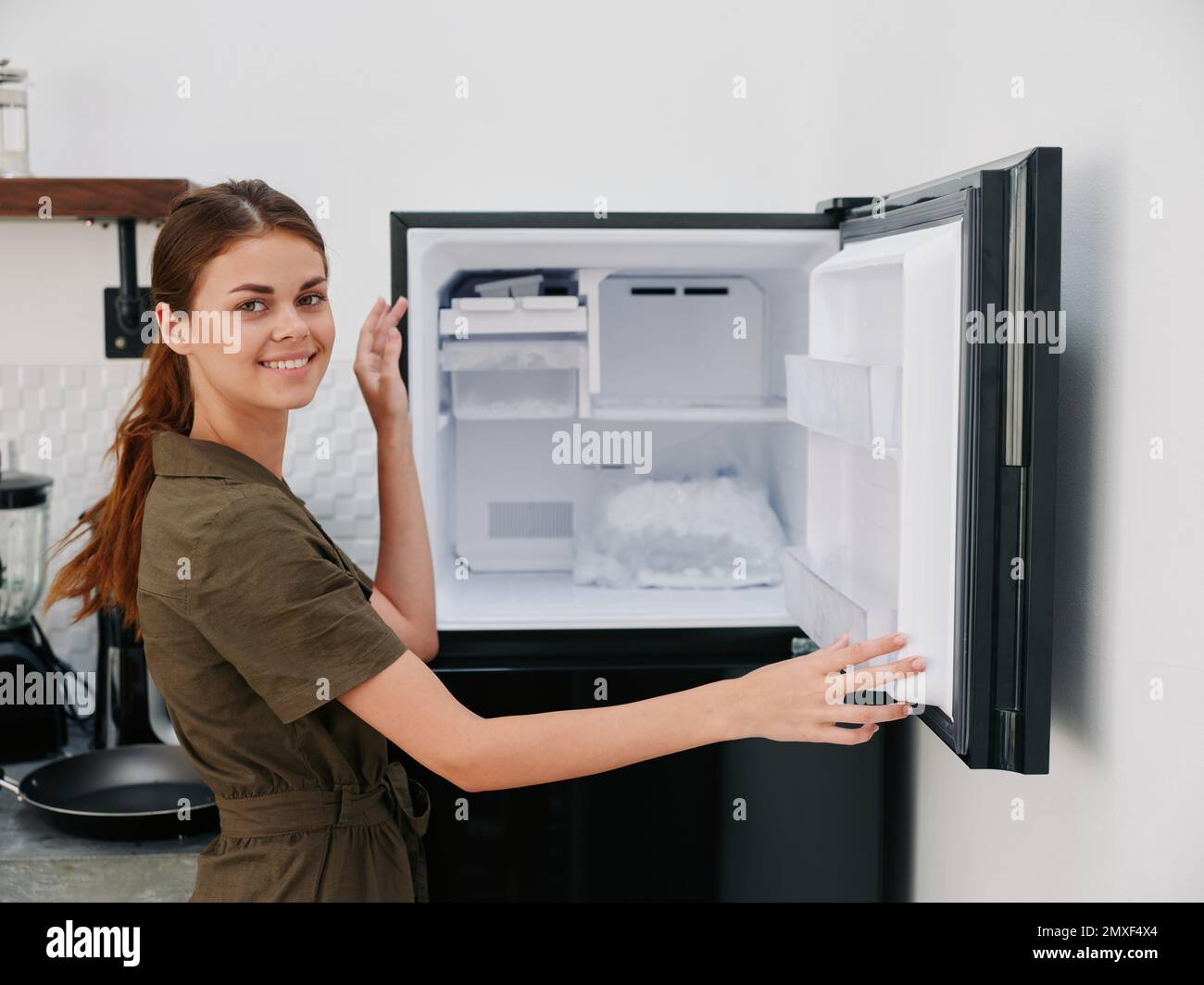 Woman smiling with teeth looking into camera in kitchen at home opened ...