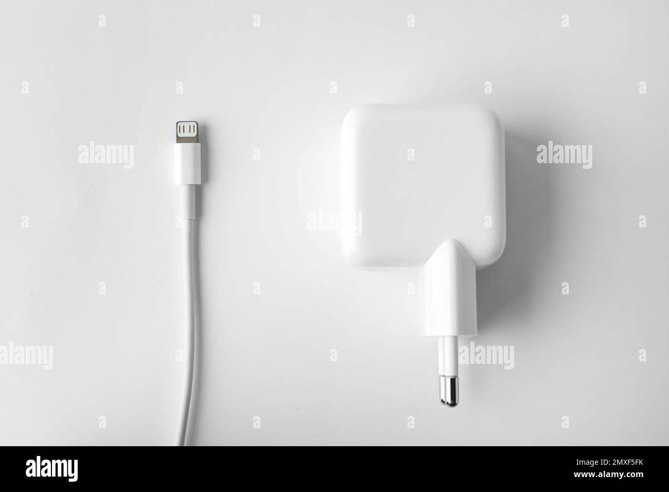 Charging cable and adapter on white background, top view Stock Photo ...
