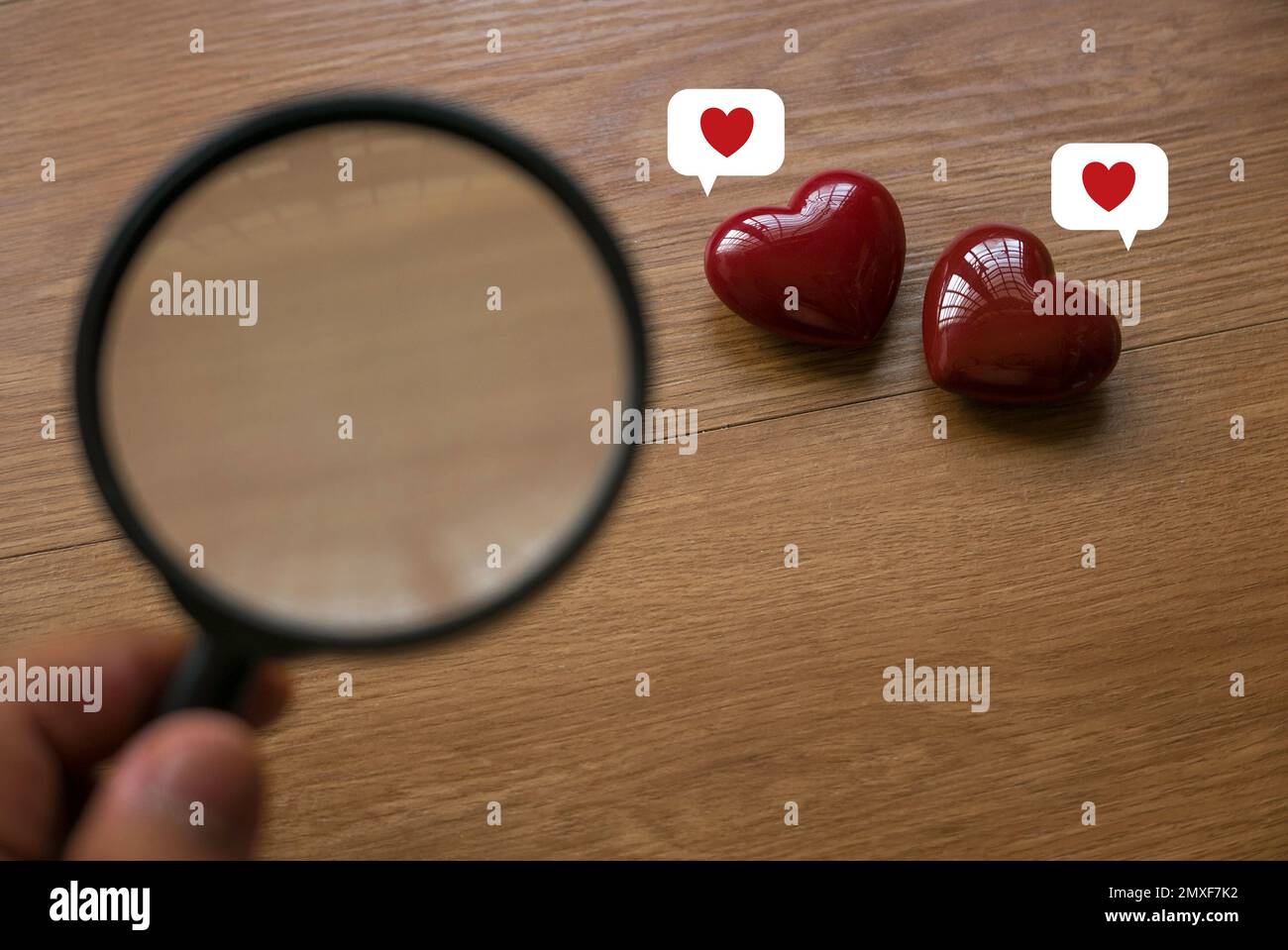 Find love concept with a hand holding a magnifying glass and a heart ...