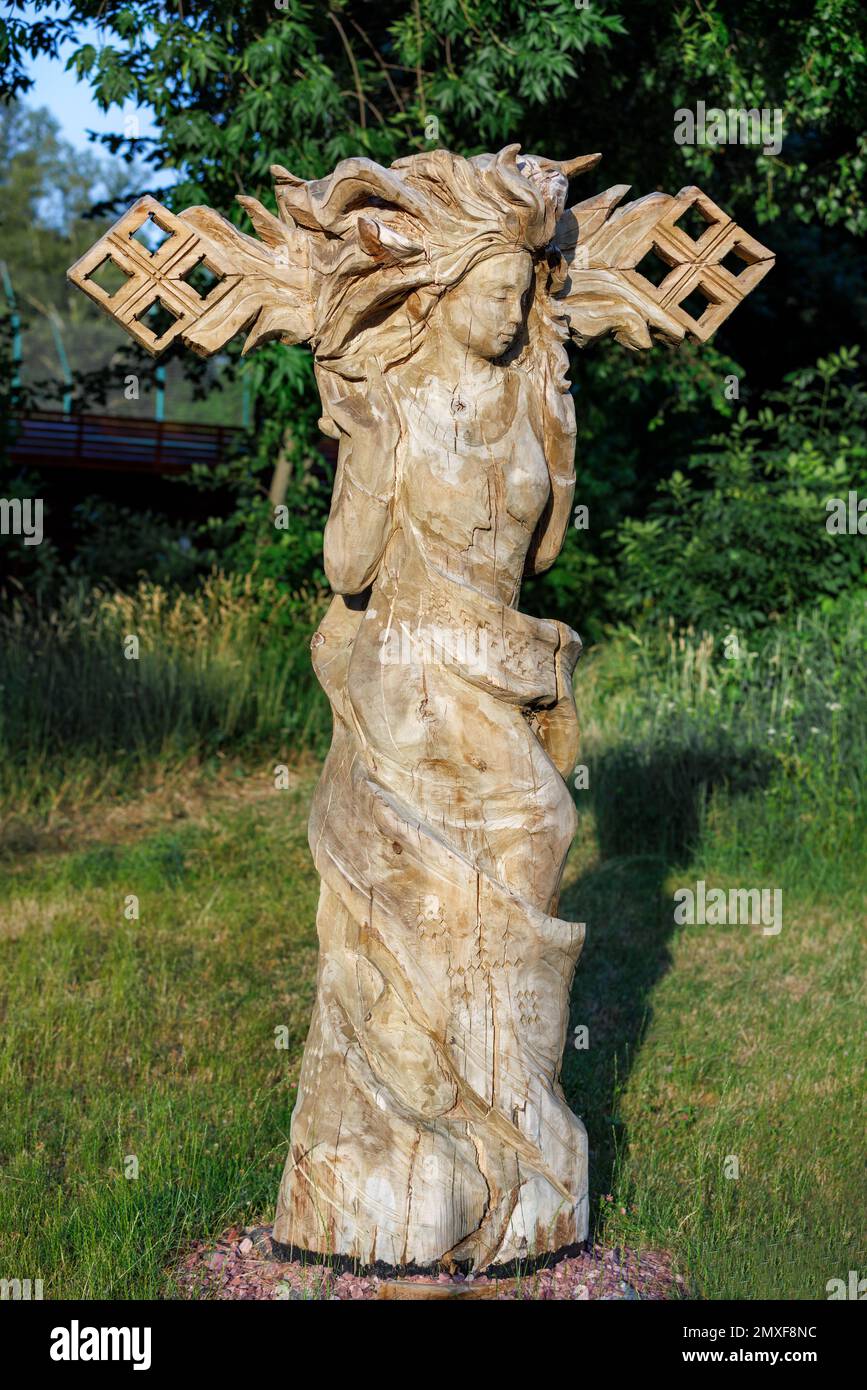 Carved wooden statue of a dancing Slavic girl in the sun against a ...